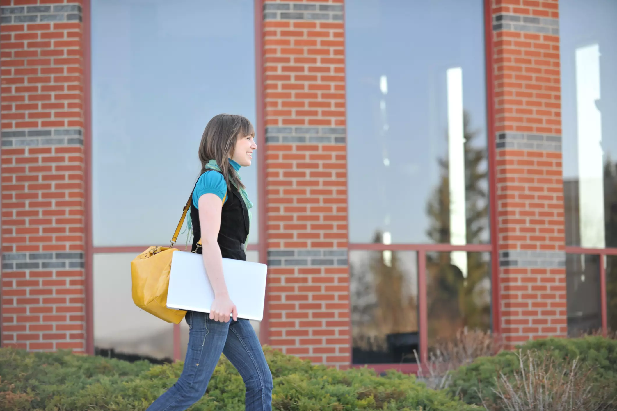 Unha estudante universitaria con TDAH atravesa o campus levando o seu portátil