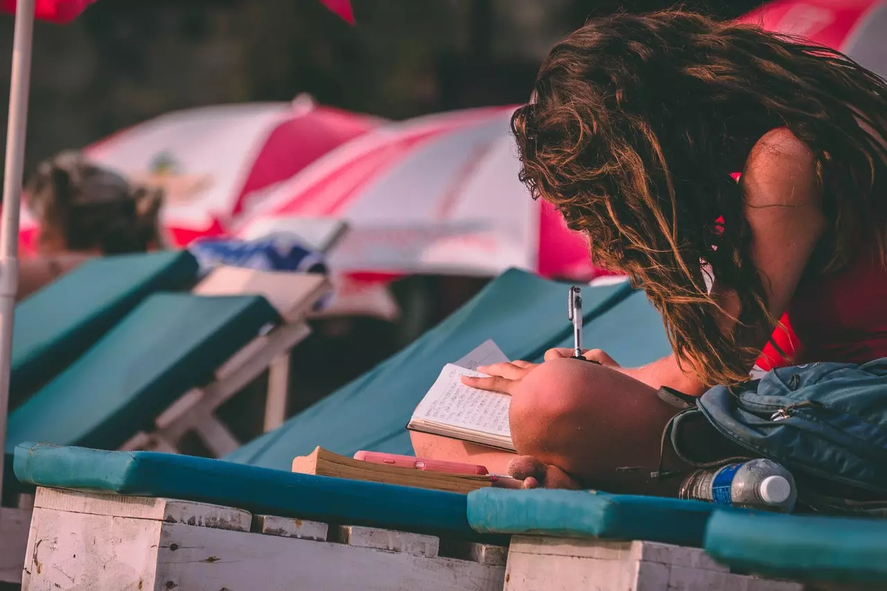 Jente som leser en bok på stranden
