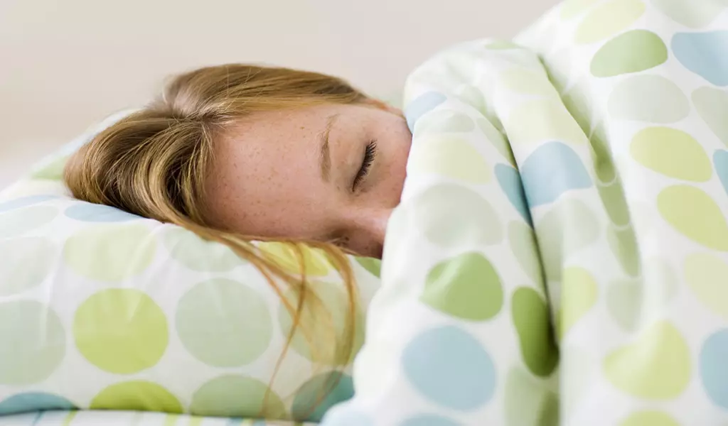 ADHD და ძილის რჩევები უფროსებისთვის, როგორიცაა ეს ქალი, რომელსაც გვერდზე სძინავს საწოლში.