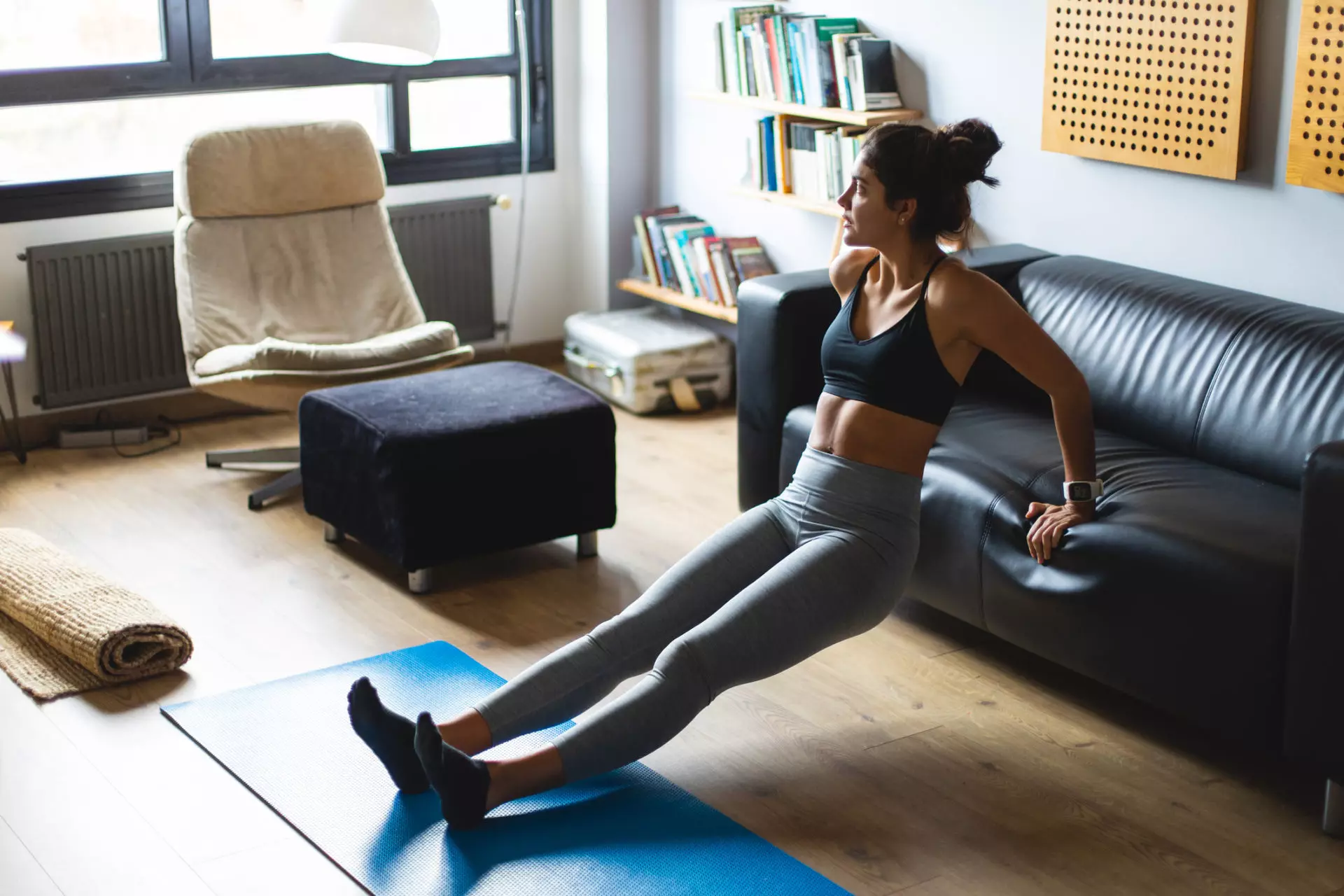 Fitnesstraining zu Hause. Gesunde fitte junge Frau, die Trizeps-Dips-Übungen im Wohnzimmer macht.