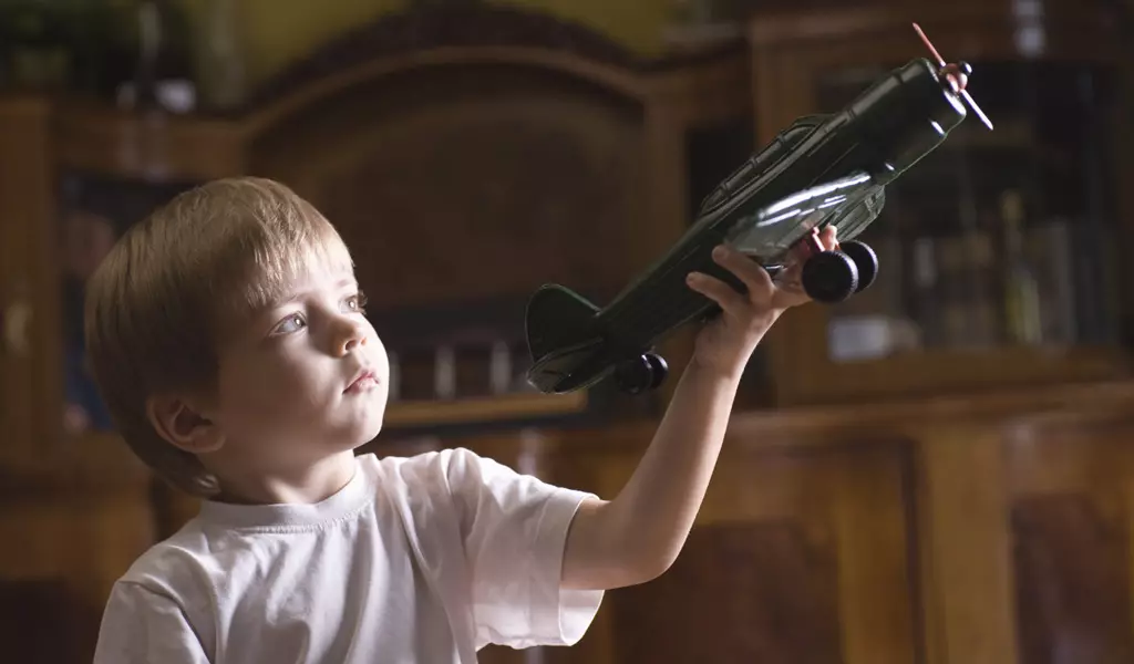 Fant z ADHD se v dnevni sobi igra z modelom letala