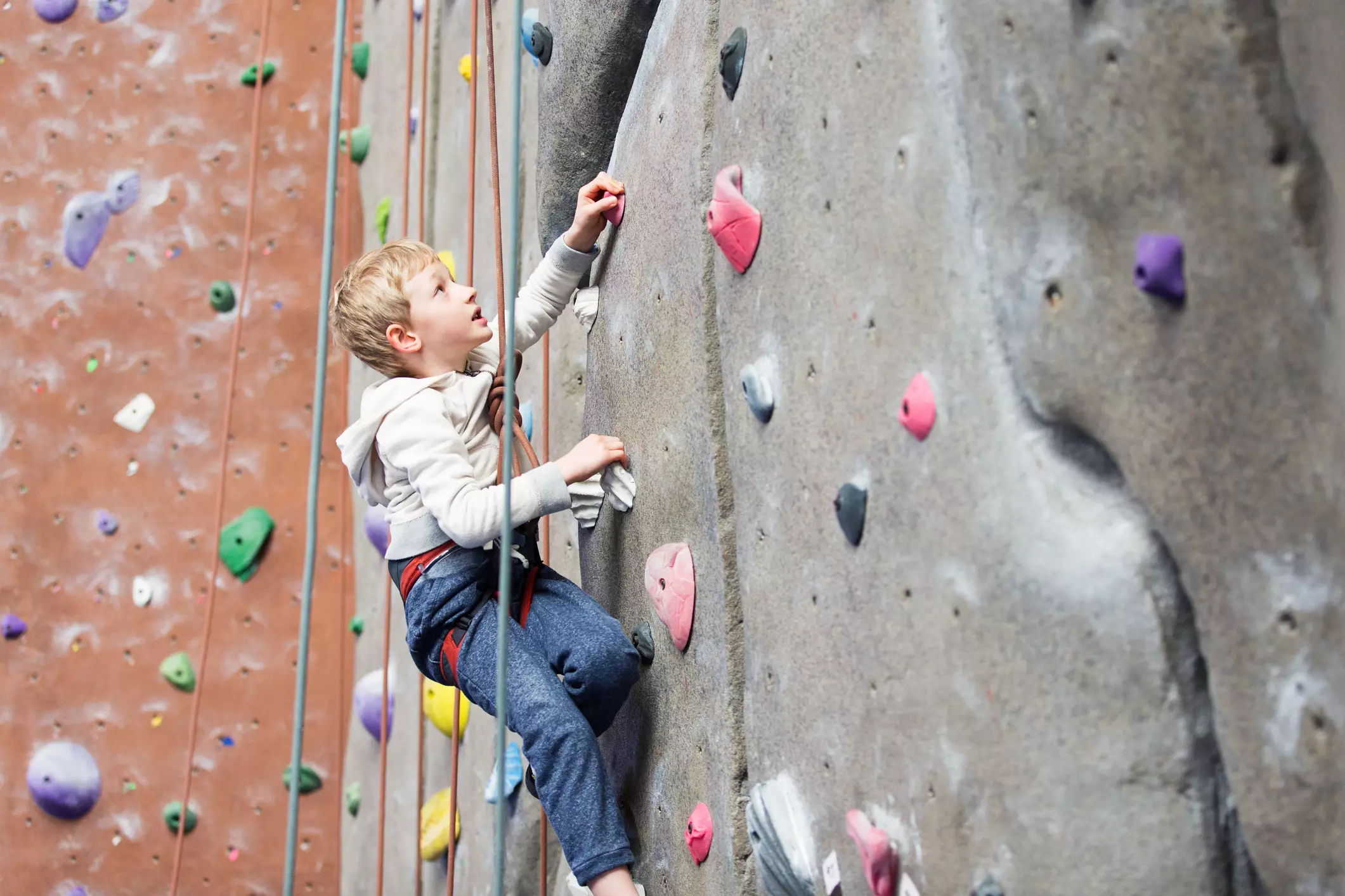 Deček z ADHD uživa v plezanju v notranji plezalni telovadnici, koncept zdravega in aktivnega življenjskega sloga