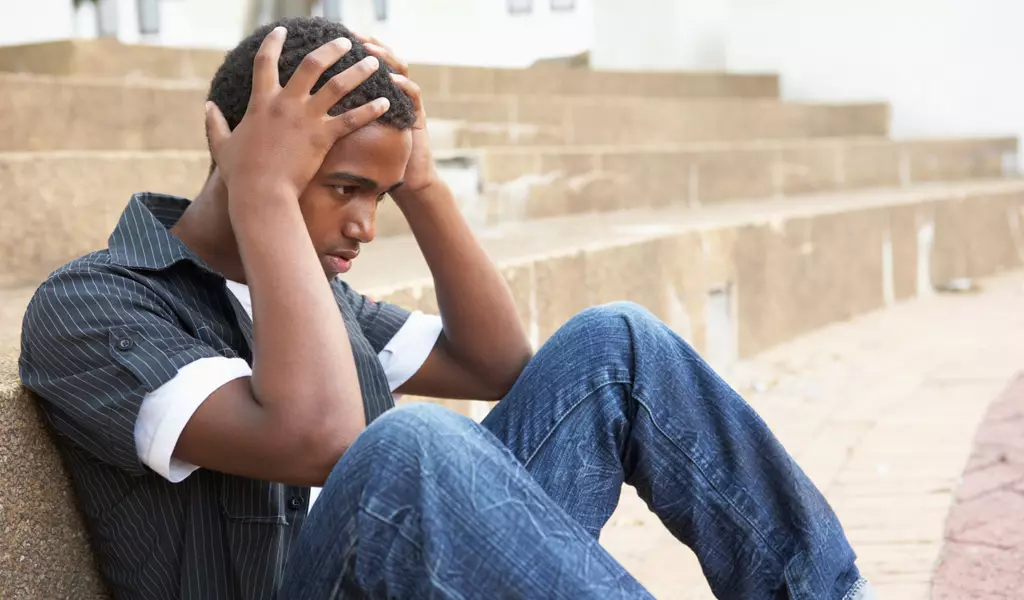 Home amb TDAH assegut a graons amb les mans al cap tractant problemes d'ira