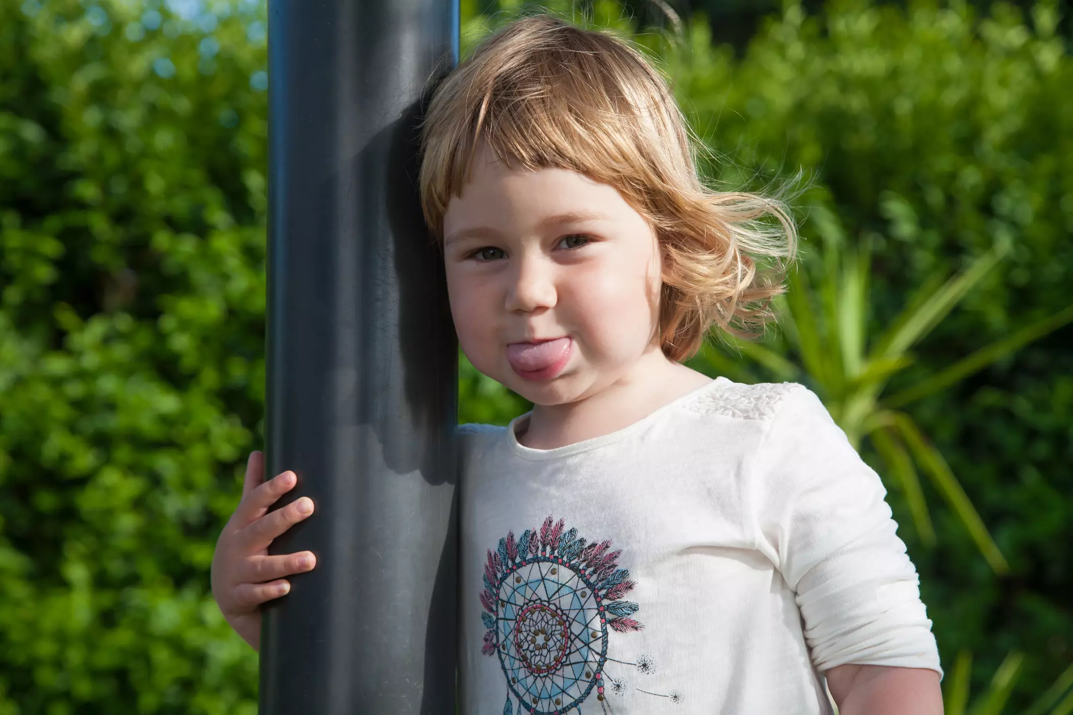 portré vicces kifejezése ADHD két éves szőke boldog mosolygó gyermek kilóg a nyelv a kertben
