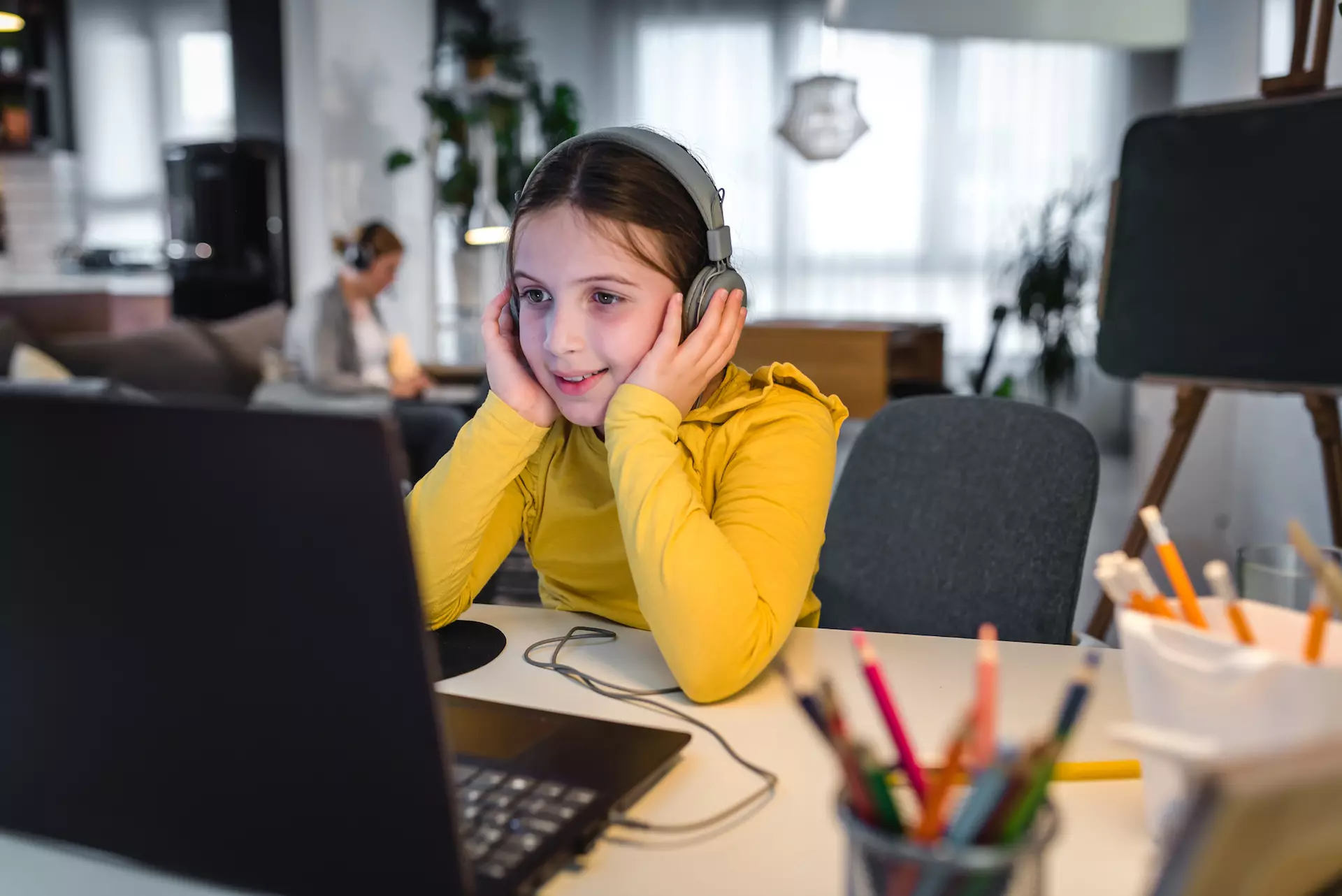Anak dengan headphone menggunakan komputer laptop untuk pembelajaran online.