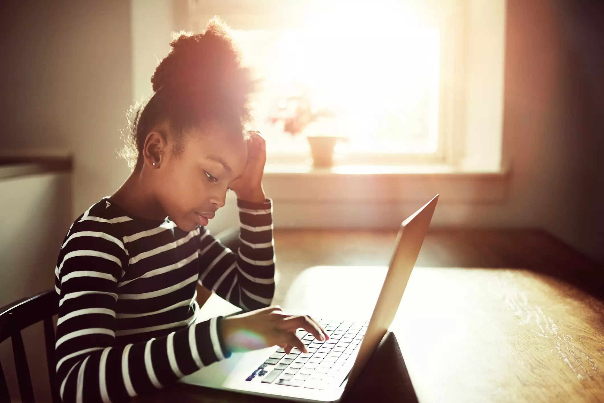 młoda dziewczyna z ADHD pracuje nad pracą domową w domu, wpisując informacje na laptopie