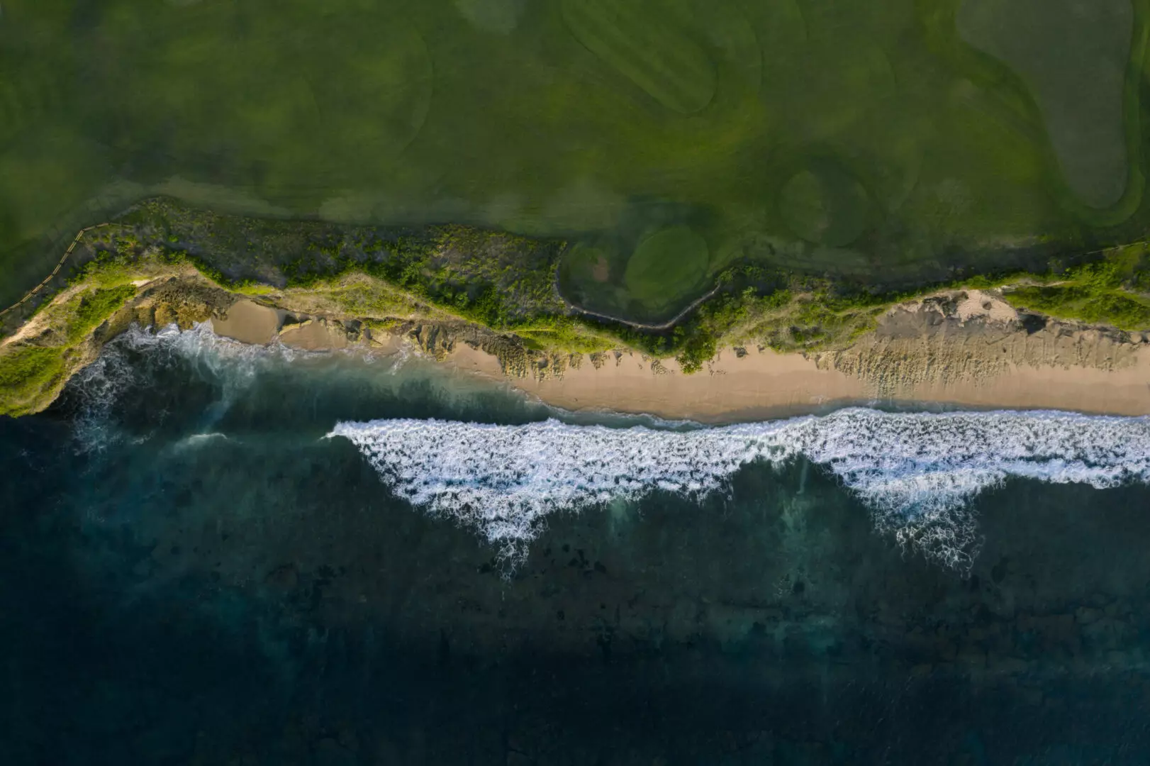 Drohnen-Luftaufnahme des schönen Sandstrandes mit Felsen.