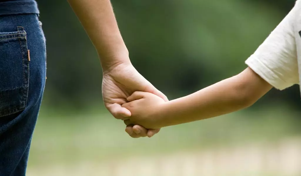Close-up da mãe segurando a mão da criança com TDAH enquanto caminhava lá fora