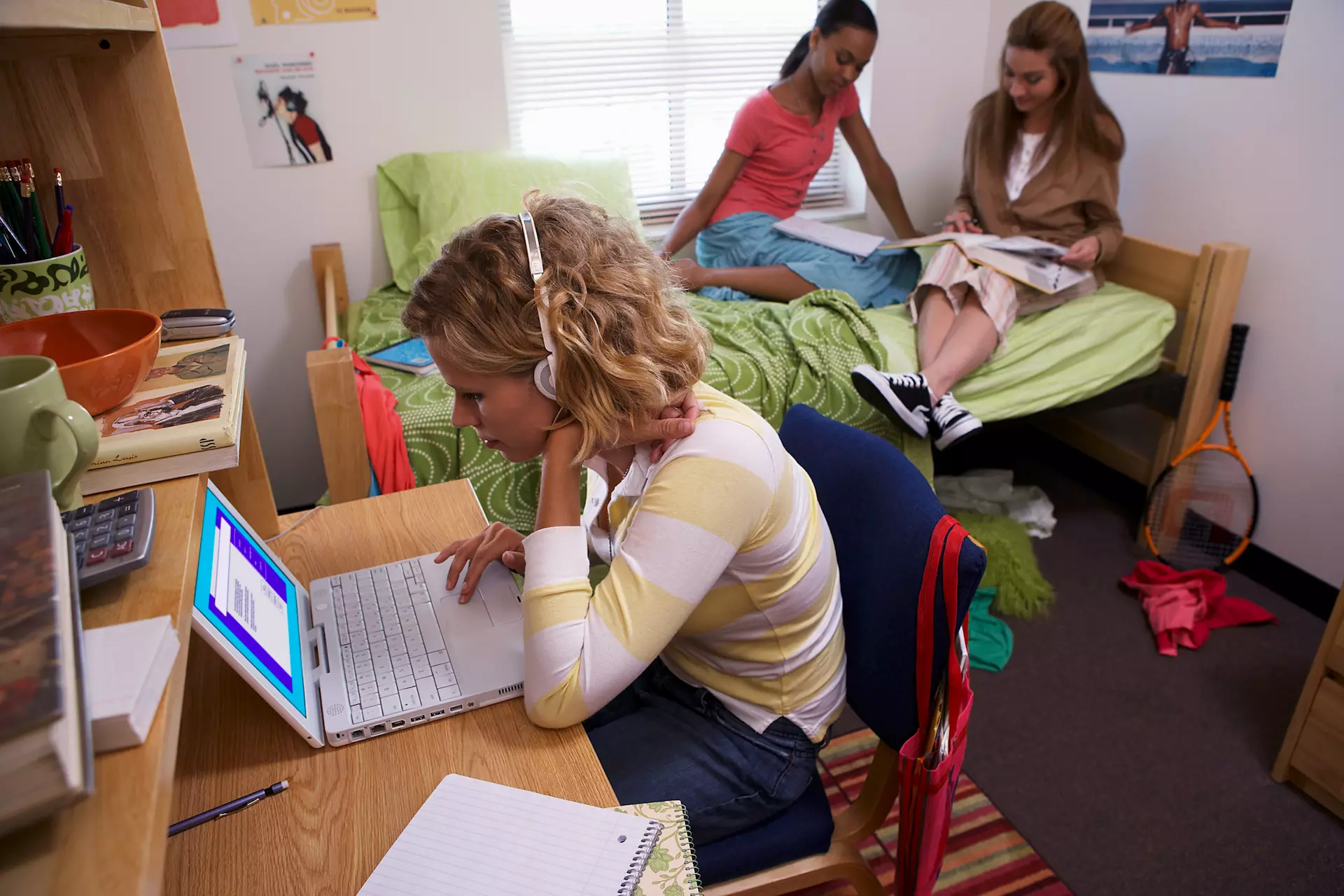 Три млади жени кои студираат во студентски дом, една на биро