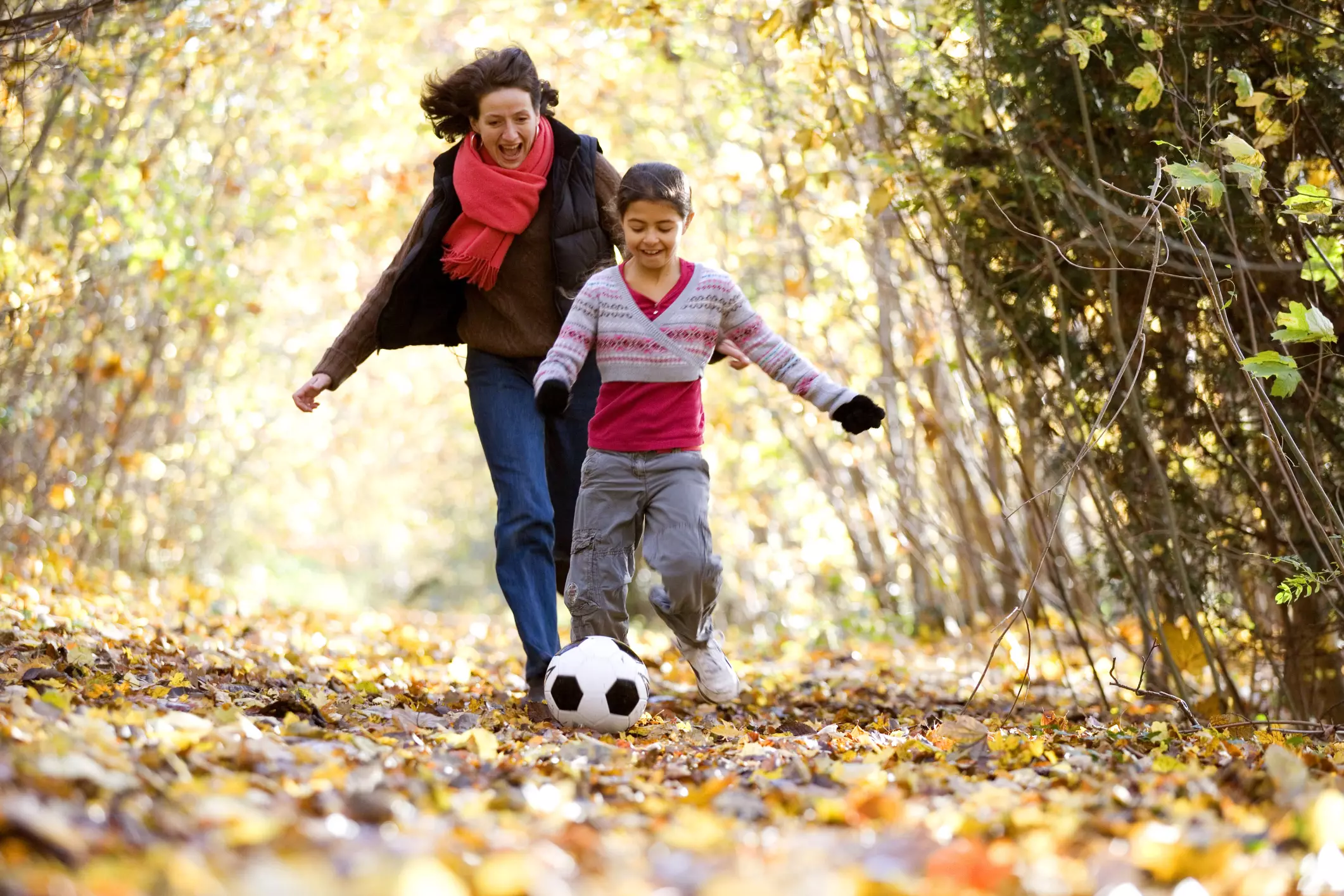 أم وابنتها يلعبان كرة القدم معًا ، مما يوضح كيف يمكن أن يكون النشاط البدني والاهتمام الفردي بمثابة علاجات طبيعية لاضطراب فرط الحركة ونقص الانتباه