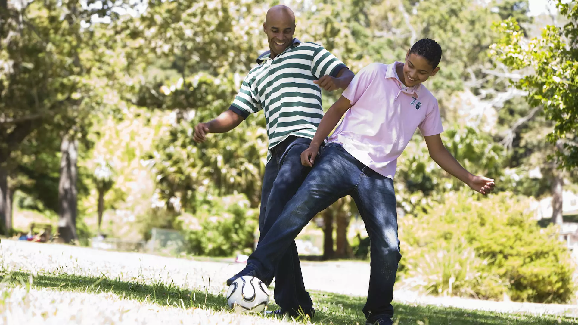 Otac koji odgaja svog tinejdžera igrajući zabavnu partiju nogometa