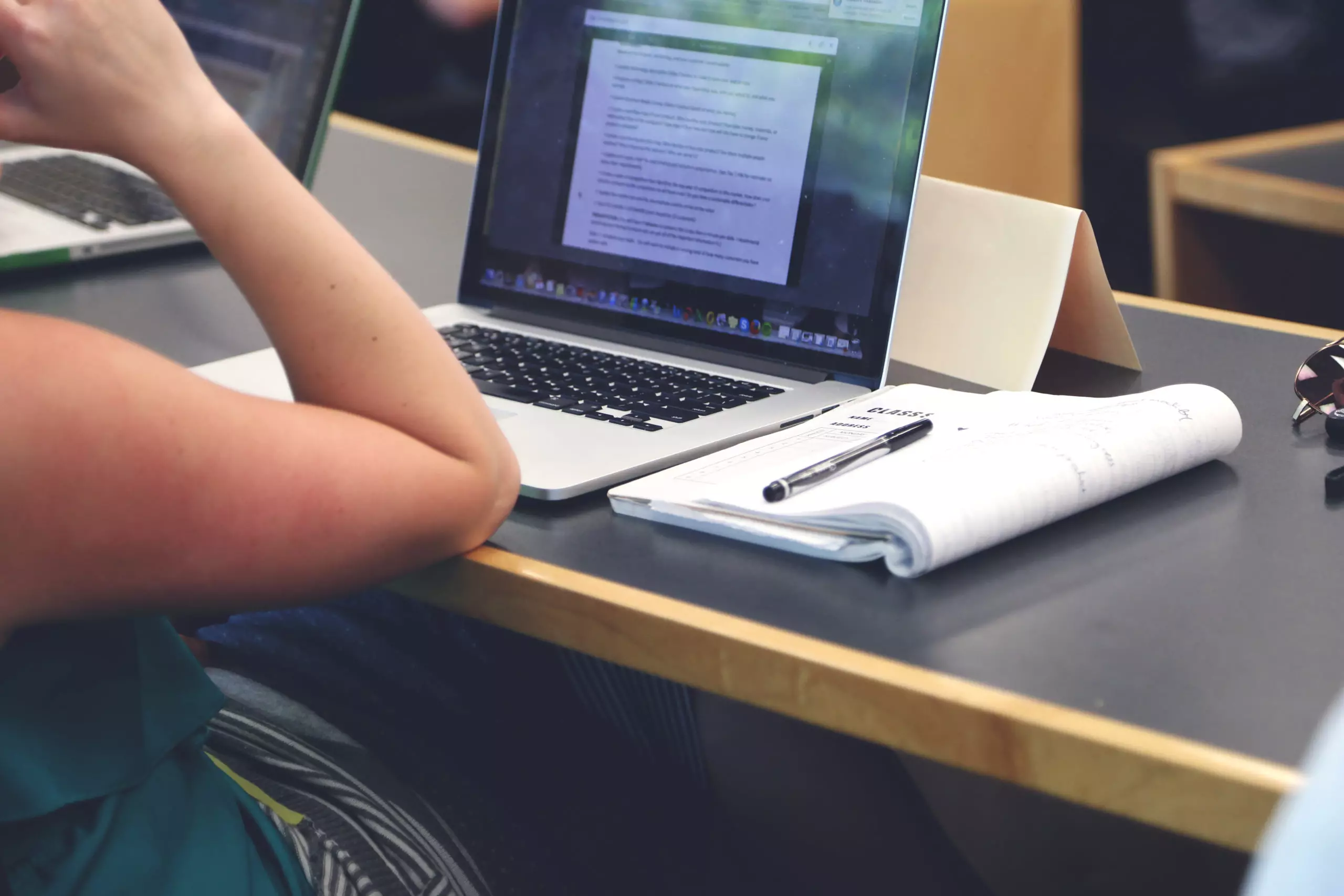 Garota com TDAH procrastinando no laptop com notebook perto dela