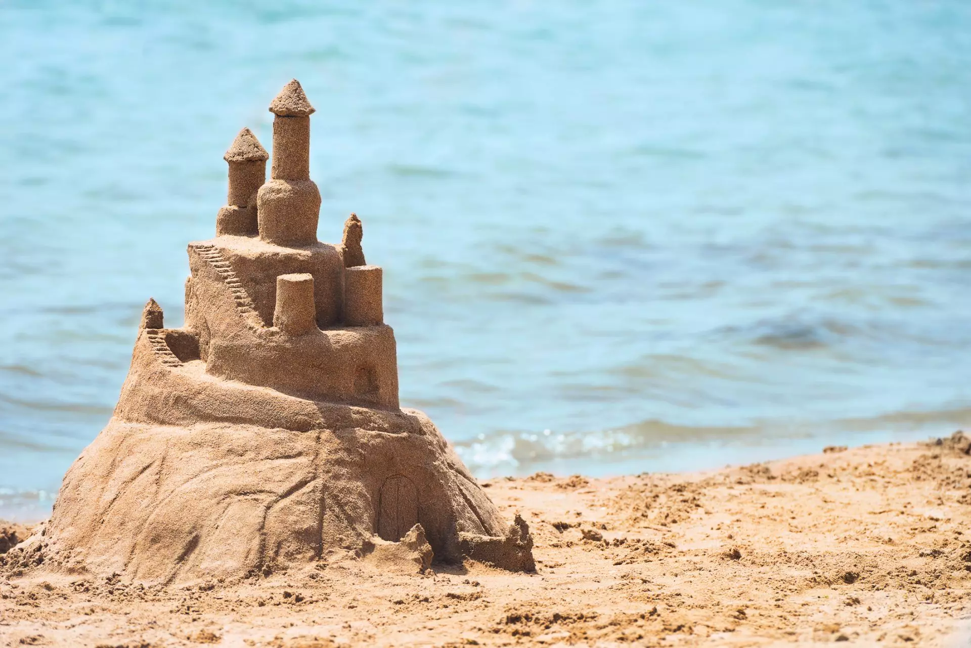 Castelo de areia da casa construída na costa sul do mar azul da praia arenosa