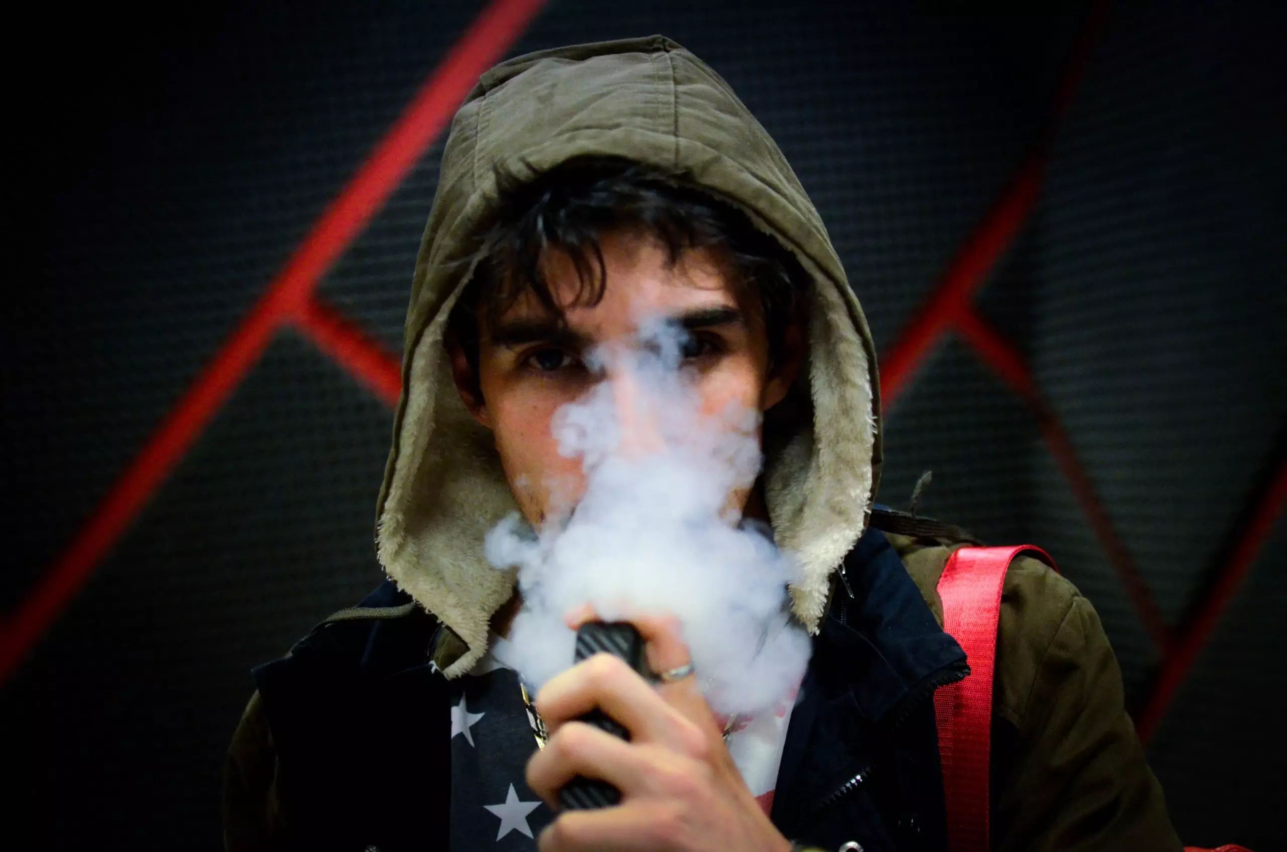 Teenager, der mit teilweise von Rauch bedecktem Gesicht dampft