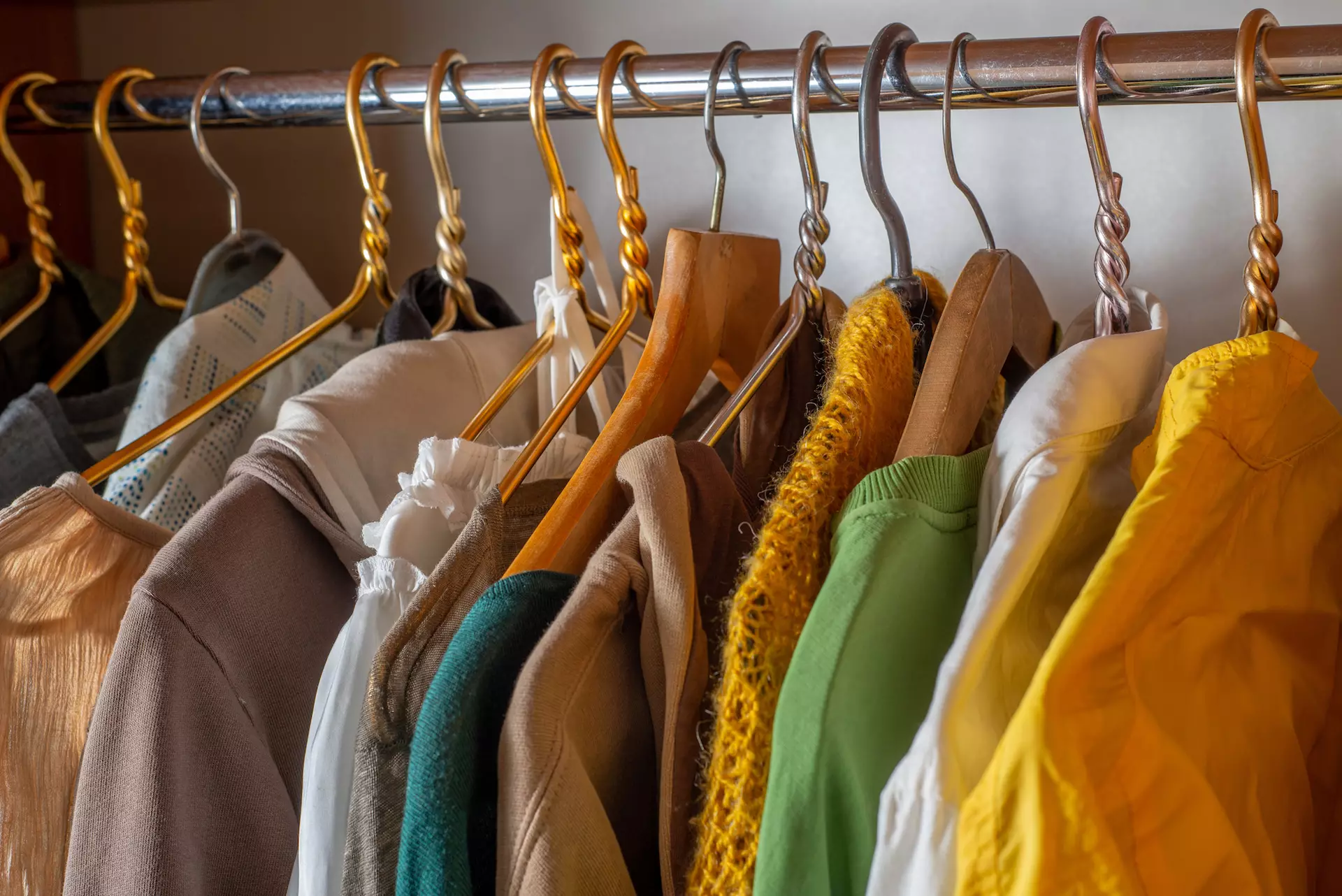 Banyak pakaian berwarna cerah di gantungan di lemari. Merapikan kabinet. Tangan kedua