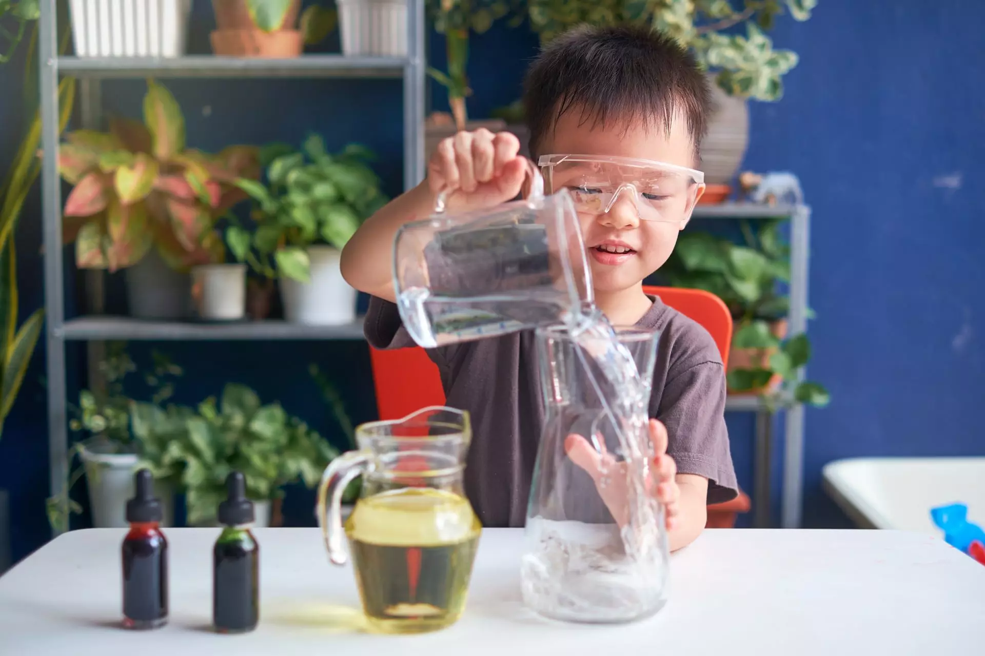 Õnnelik väike Aasia koolilaps, kes õpib loodusteadusi, teeb isetehtud laavalampide teaduskatset õli, vee ja toiduvärvidega, lastesõbralikke lõbusaid ja lihtsaid loodusteaduslikke katseid kodus.