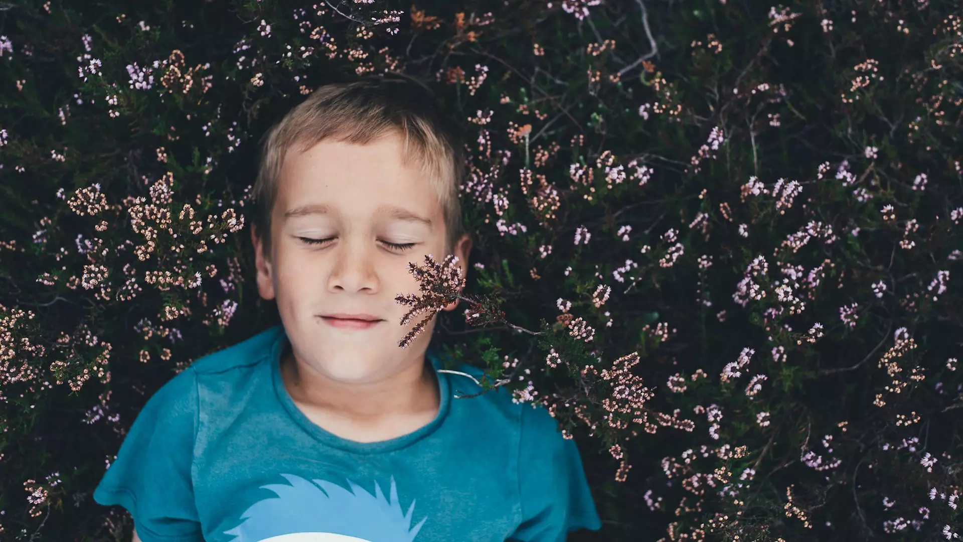 Vaikas guli žolėje ir atlieka sąmoningumo pratimus